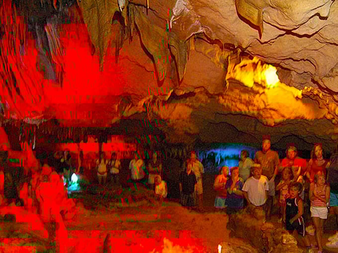 Dramatic red and gold lighting transforms the cavern into nature's own theater, where stalactites perform their slow-motion ballet.