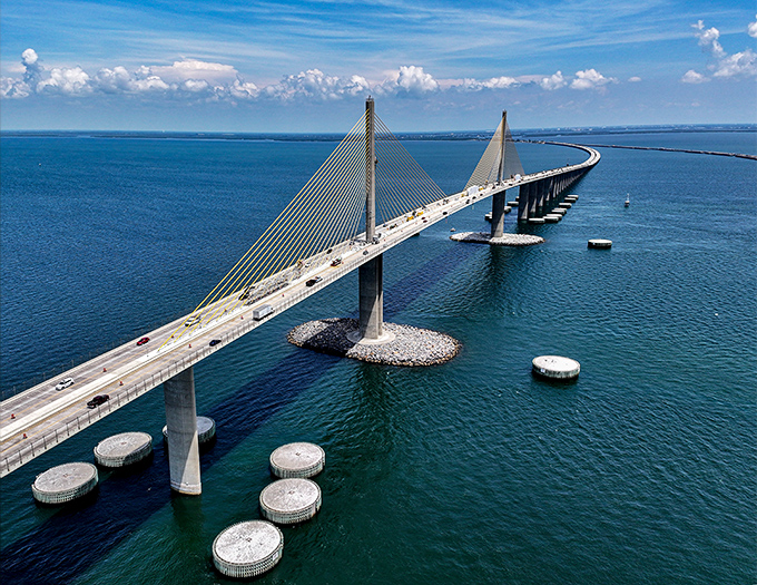 The Sunshine Skyway Bridge stretches majestically across Tampa Bay, its golden cables reaching skyward like sunbeams frozen in architectural perfection.