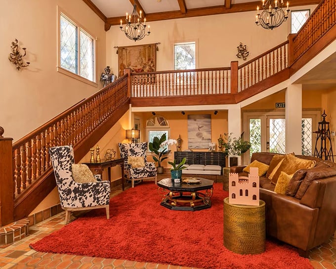 A plush red carpet anchors this living space, where cowhide chairs add unexpected flair to the castle's eclectic royal vibe.