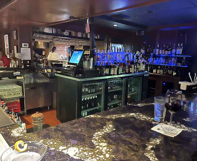The bar area gleams with bottles and possibilities, ready to mix classic cocktails with professional precision and care.