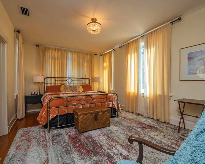 Sunlight streams through sheer curtains in this serene bedroom, where warm wood floors contrast with cool, restful wall colors.