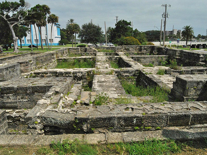 Ancient stone foundations tell silent stories of early settlers, their carefully laid patterns now home to persistent greenery reclaiming its territory.