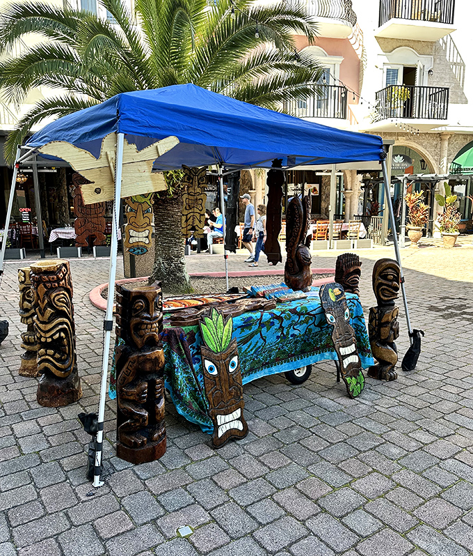 Carved tiki statues stand guard at a vendor's booth, blending Polynesian influence with the village's international flair.