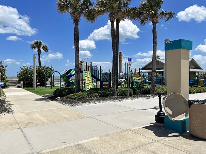 A colorful playground waits beneath swaying palms, promising young adventurers a break from sandcastles and splashing in the waves.