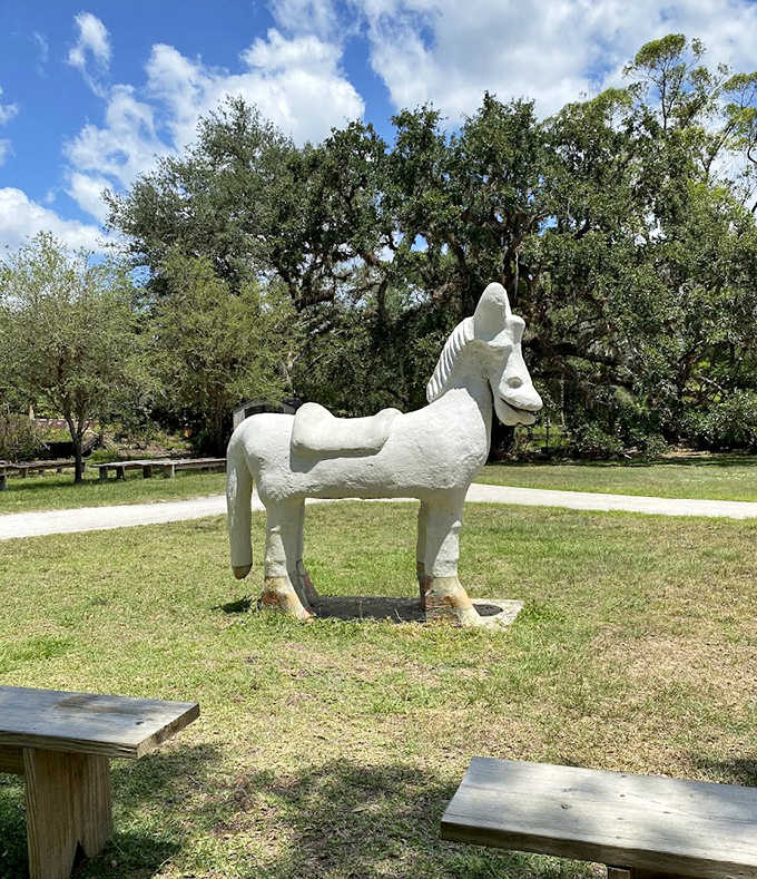 A whimsical white horse statue grazes peacefully on the lawn, its simplistic design adding to the property's charming collection of outdoor art.