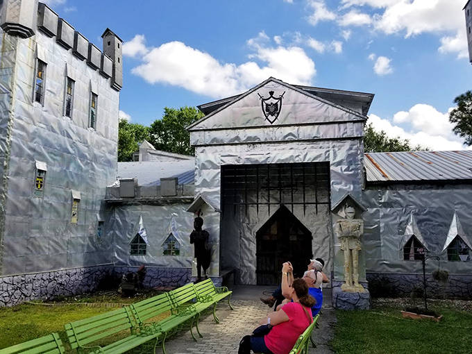 Bright green benches offer front-row seats to the castle's silvery splendor, inviting visitors to rest while soaking in this architectural oddity.