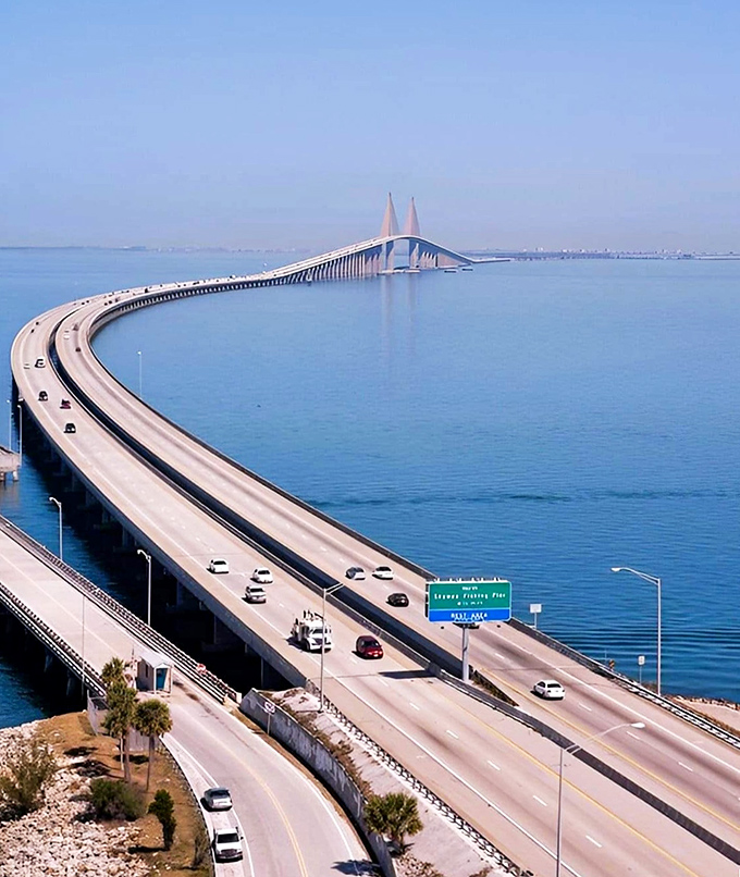 From above, the bridge's graceful curve creates a perfect arc across the blue waters, connecting communities while offering drivers a rollercoaster-like thrill.