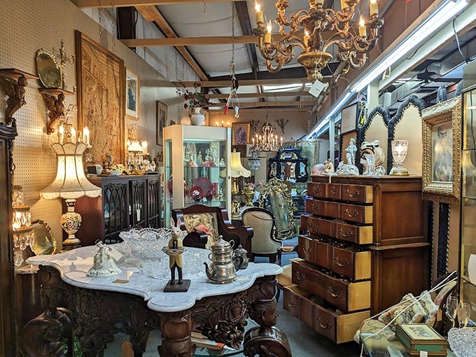 Chandeliers cast a golden glow over this antique wonderland, where ornate furniture and vintage treasures compete for attention in delightful disarray.