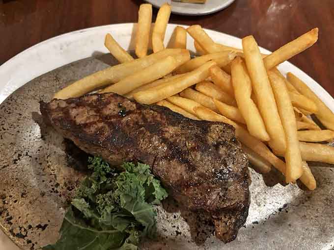 The New York Strip arrives with perfect grill marks and that ideal pink center that steak dreams are made of.