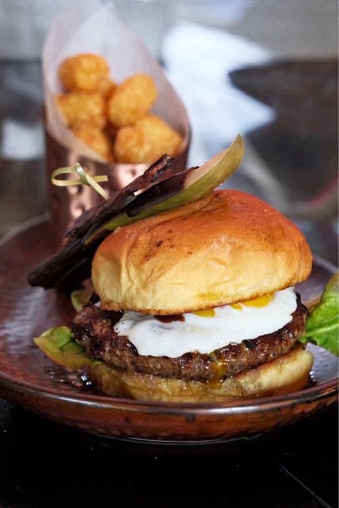 The Tour de Toothsome Burger comes with enough toppings to require architectural support, and yes, those are tots.