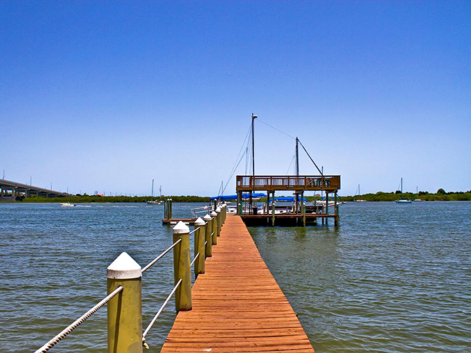 A wooden boardwalk stretches toward adventure, its sun-bleached planks leading visitors to fishing spots and breathtaking views.