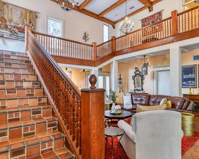 The grand foyer opens to a two-story living space where wooden staircases and balconies create a medieval-meets-modern atmosphere.