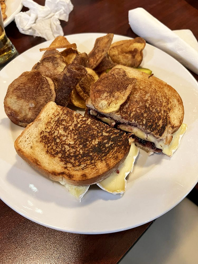 The grilled cheese sandwich arrives golden-brown and oozing with melted goodness, accompanied by homemade potato chips that shatter satisfyingly with each bite.