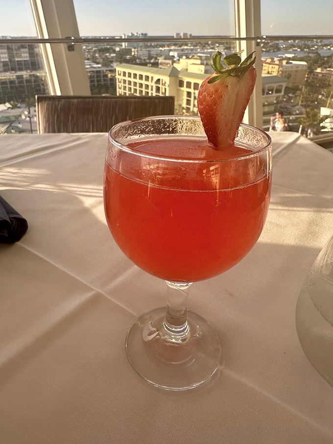 The Strawberry Bliss cocktail catches golden hour light, its ruby hue promising fruity refreshment with a view that keeps improving.