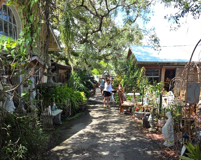 Sunlight dapples this garden-like pathway between vendor stalls, creating a magical treasure-hunting experience beneath Florida's lush greenery.