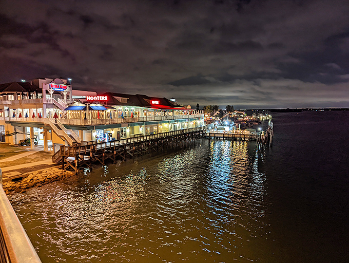 As darkness falls, John's Pass transforms into a twinkling wonderland where restaurant lights dance across the water like fallen stars.