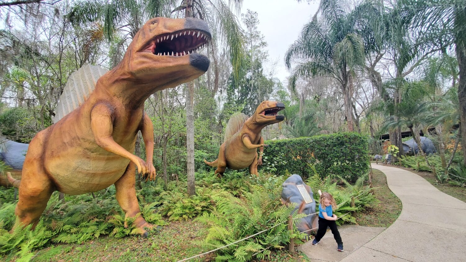 A garden filled with a variety dinosaur statues.