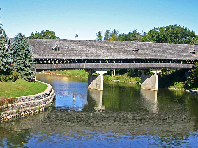 The majestic Holz Br&uuml;cke spans the Cass River like a wooden guardian, welcoming visitors to Frankenmuth's Bavarian wonderland with old-world charm.