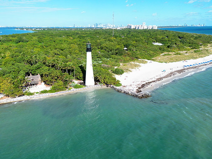 A pristine white tower rises dramatically from Key Biscayne's lush landscape, with Miami's skyline shimmering in the distance like a mirage.