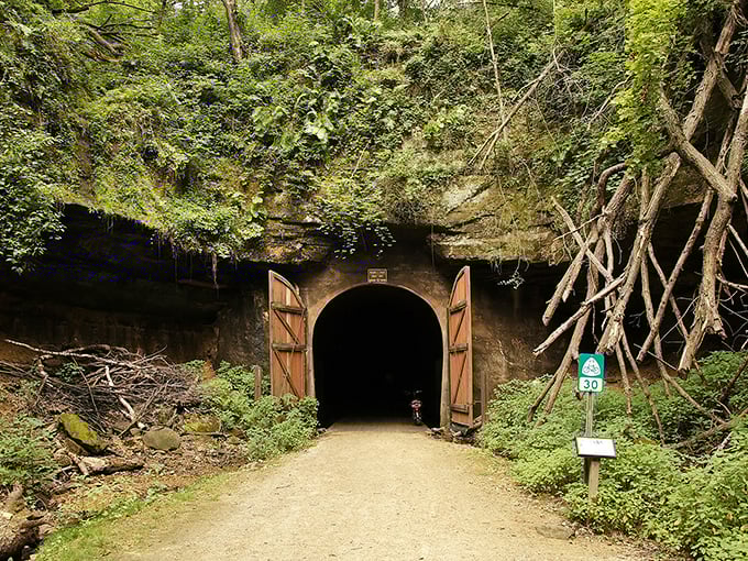 Tunnel entrance beckons with mystery &ndash; massive wooden doors frame a portal to Wisconsin's railroad past, nature slowly reclaiming its edges.