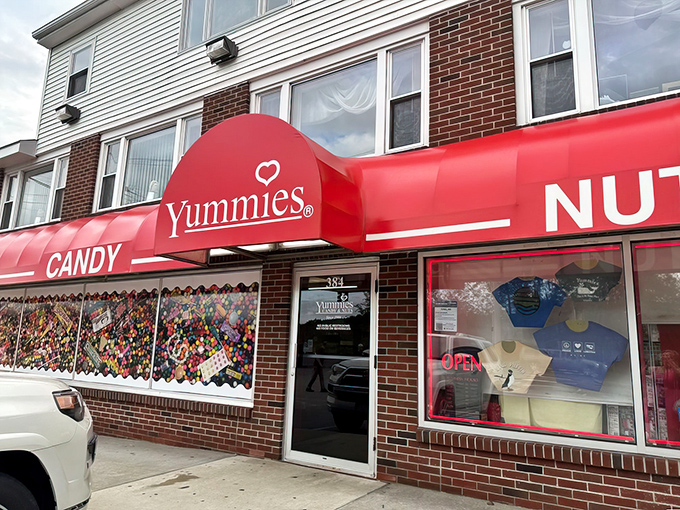 The vibrant red storefront of Yummies Candy & Nuts promises sweet adventures with its heart-adorned logo and bold claim of 10,000 pounds on display.