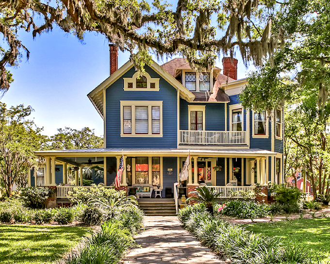 A grand Victorian lady dressed in blue, this historic mansion welcomes visitors with Southern charm and Spanish moss elegance.