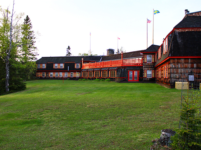 The historic Naniboujou Lodge stands proudly against Minnesota's northern sky, its weathered shingles and bold red trim defying conventional lodge aesthetics.