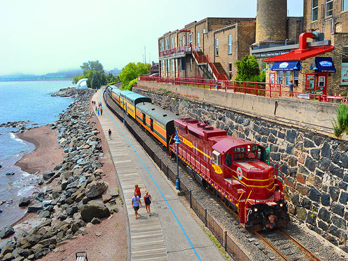 The crimson engine of the North Shore Scenic Railroad hugs Lake Superior's rocky shoreline, a moving postcard of Minnesota's natural grandeur.