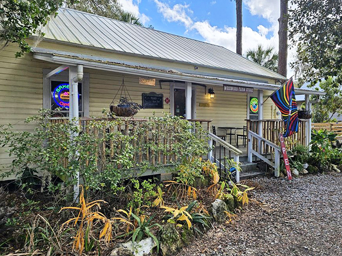 The charming yellow exterior of Mosswood Farm Store beckons with rustic appeal and a rainbow flag, promising delicious adventures within.