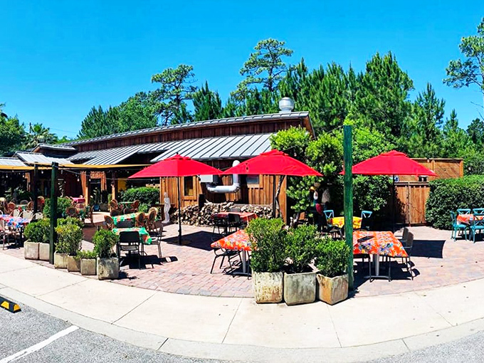 Rustic charm meets coastal cool at Louis Louis' exterior, where vibrant red umbrellas invite you to slow down and savor life.