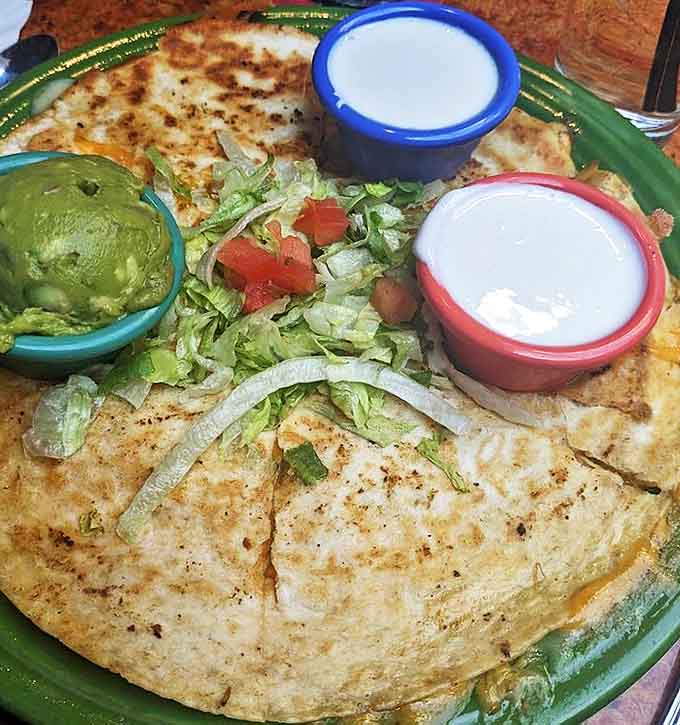 This isn't your average quesadilla – it's a golden-brown envelope of melty cheese perfection, accompanied by the holy trinity of Mexican condiments in colorful bowls.