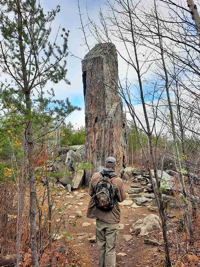 A hiker approaches the massive stone sentinel, providing scale that emphasizes just how impressive this natural monument truly is.