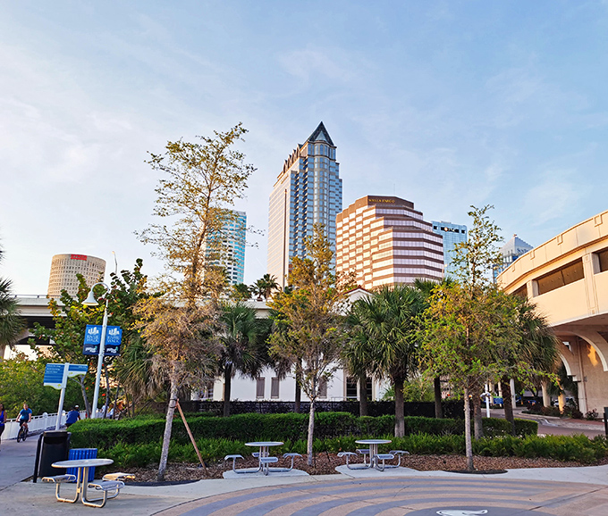 Picnic tables nestled among palm trees offer the perfect spot for people-watching or enjoying takeout from nearby restaurants. Urban dining with natural air conditioning!