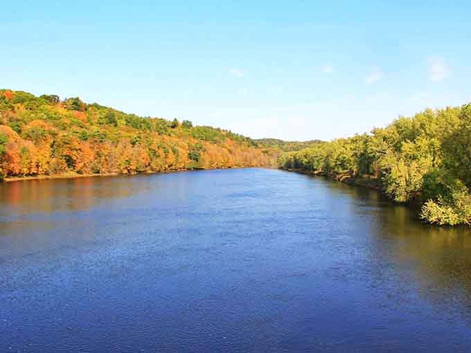 The St. Croix River paints a serene portrait of Wisconsin's natural splendor, its waters reflecting autumn's fiery palette in a double display of seasonal magic.