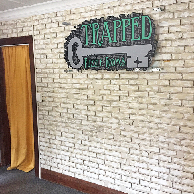 The Trapped Puzzle Rooms logo stands out against exposed brick, marking the threshold between the ordinary world and magical adventure.