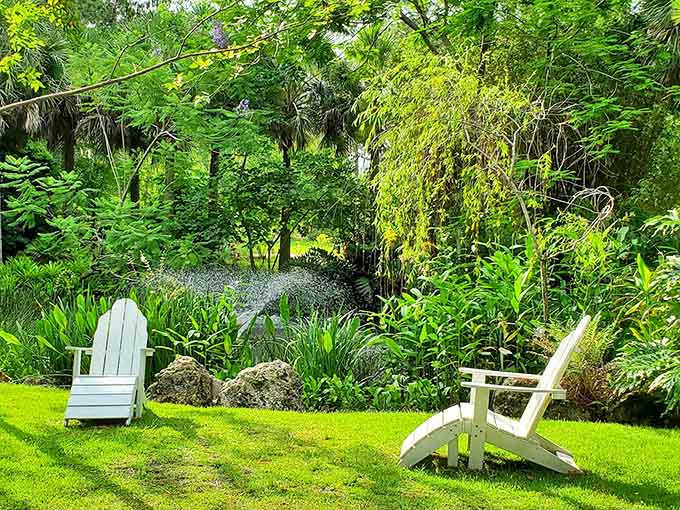 White Adirondack chairs on perfect green grass create a scene so peaceful it should come with a prescription for stress relief and a side of lemonade.