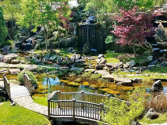 Water dances over rocks in this meticulously designed garden oasis, where wooden bridges invite contemplation of nature's perfect design.