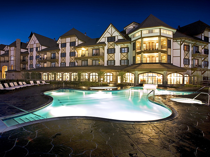 The outdoor pool glows with inviting blue light against the resort's European-inspired architecture, creating a magical evening swim opportunity.
