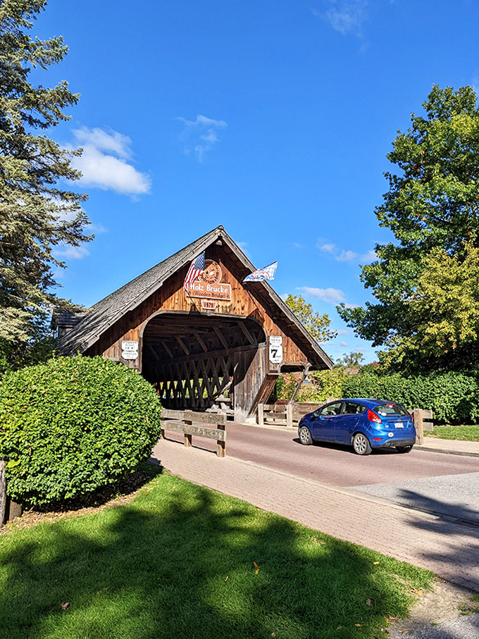 Even modern vehicles seem to time-travel as they pass through this wooden wonder, creating a charming contrast of past craftsmanship and present-day convenience.