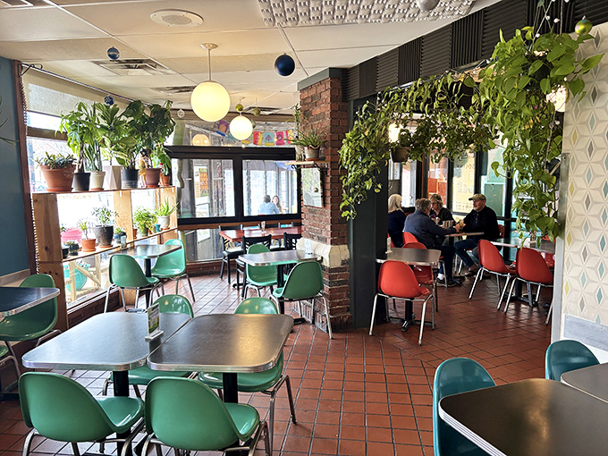 Plants cascade from shelves while globe lights cast a warm glow over the dining area, creating an urban jungle vibe that makes every meal feel like an escape.