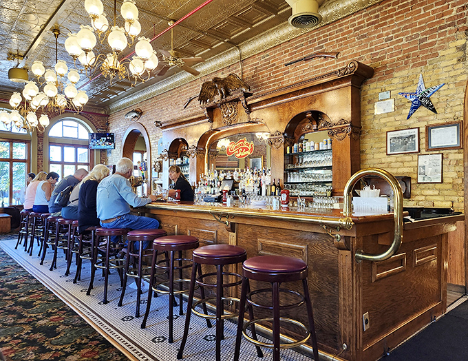 The polished wooden bar stands like a captain's deck, where stories flow as freely as the drinks beneath the warm glow of vintage lighting.