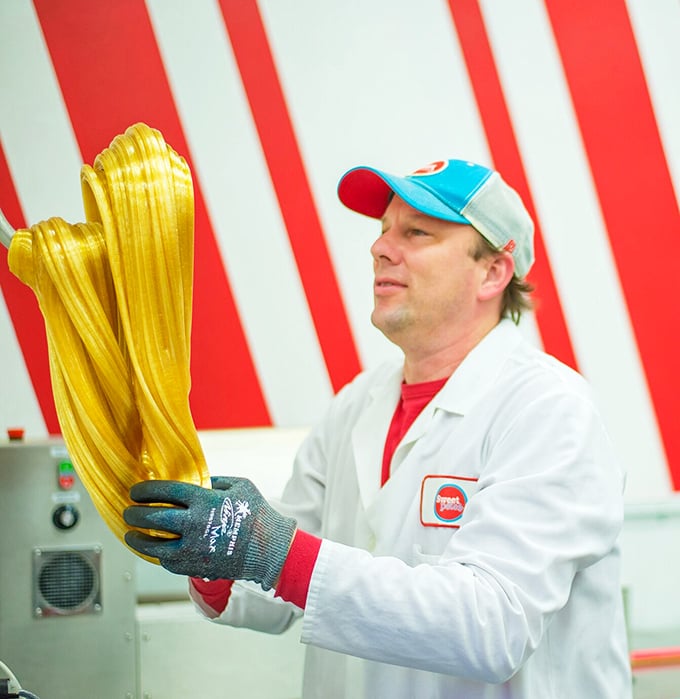 The taffy whisperer at work! Watching this golden strand transform into lollipops is better than meditation for candy lovers.