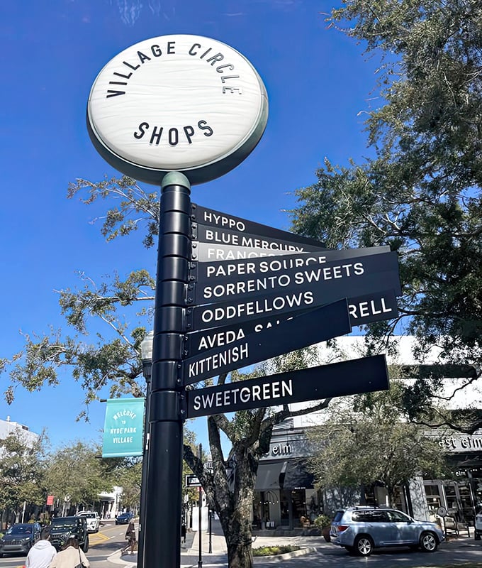 The Village Circle directory stands as a stylish roadmap to retail therapy, pointing shoppers toward their next discovery with sleek black signage against the blue Tampa sky.