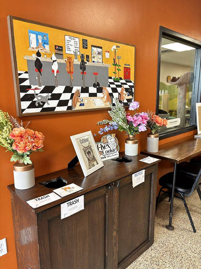 Whimsical cat artwork and fresh flowers add charm to this corner of the caf&eacute;, where even the trash bins are labeled with care.