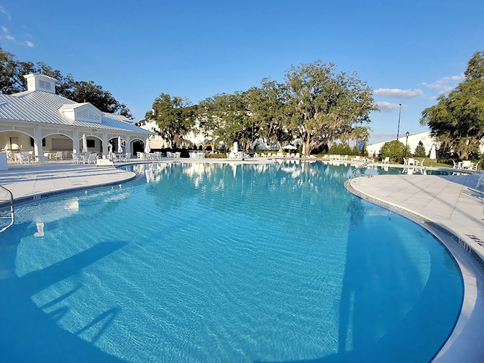 The resort pool stretches like a blue oasis, practically whispering "cancel your afternoon plans and bring a good book."