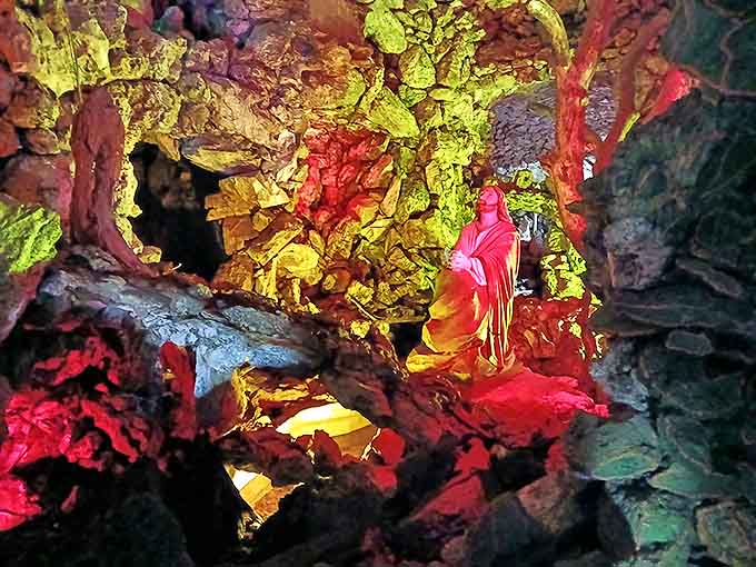 Colorful lighting transforms the interior shrines into dramatic tableaux, playing with shadow and light in the cave's cool darkness.