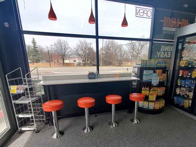Window seating with orange stools offers prime people-watching real estate while you devour your meal.
