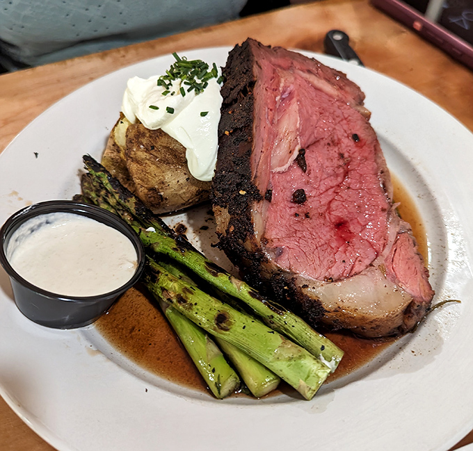 Prime rib cooked to rosy perfection, accompanied by grilled asparagus and a loaded baked potato &ndash; a classic done right for those special occasions.