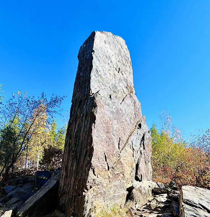 Against a perfect blue canvas, the monolith reaches skyward, its weathered surface telling tales of geological drama.