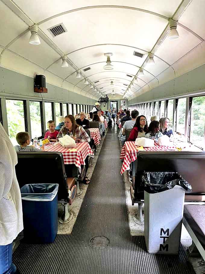 Families gather around checkered tablecloths in the dining car, where meals become memories against a backdrop of ever-changing scenery.